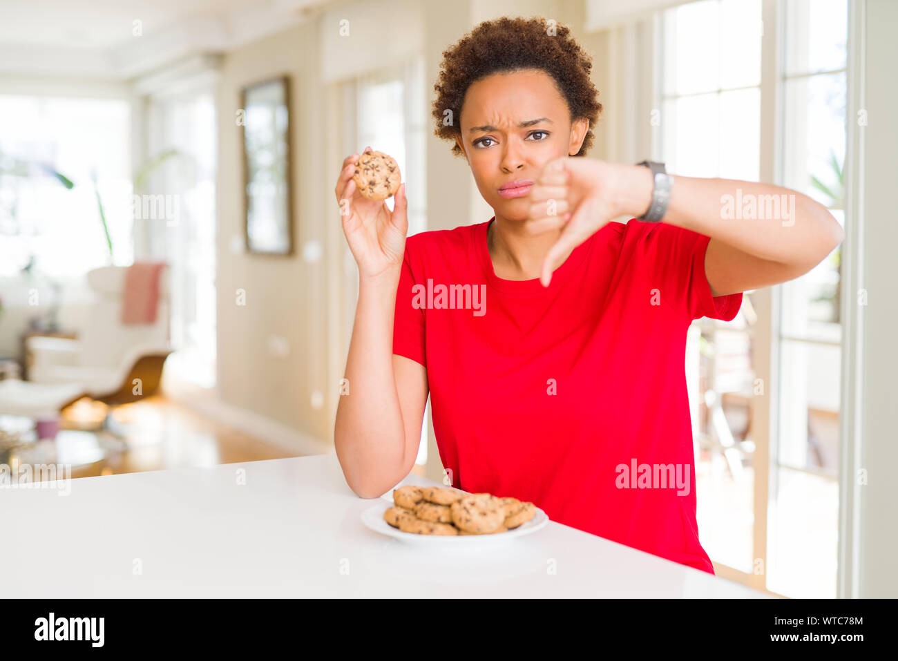 Young african american woman eating chocolate chips cookies with angry ...