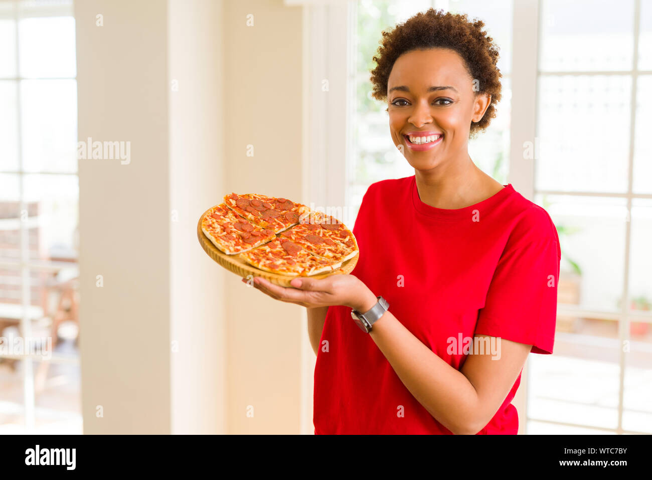 Beautiful young african american woman showing homemade tasty pizza ...