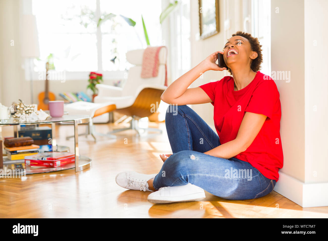 Beautiful young african american woman sitting on the floor having a ...