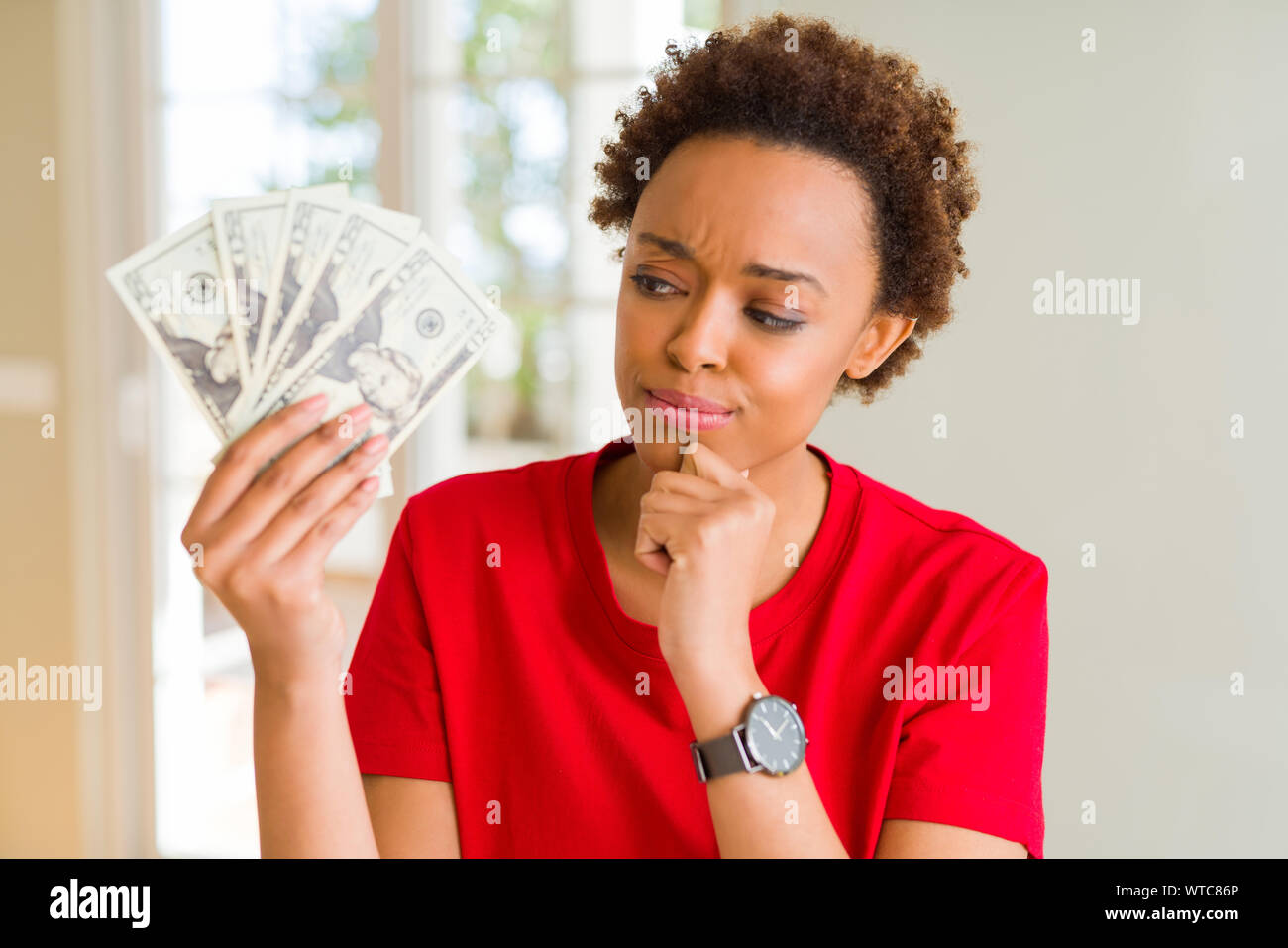 Young african american woman holding bank notes of twenty dollars ...