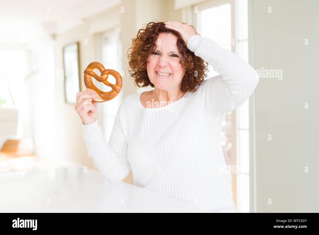 Senior woman eating german salty pastry pretzel for octoberfest ...