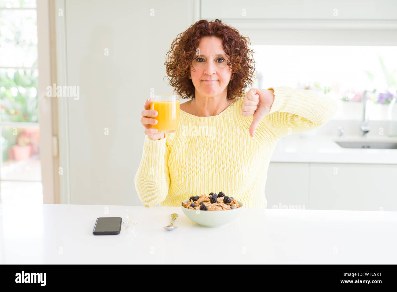 Senior woman eating healthy breakfast in the morning at home with angry ...