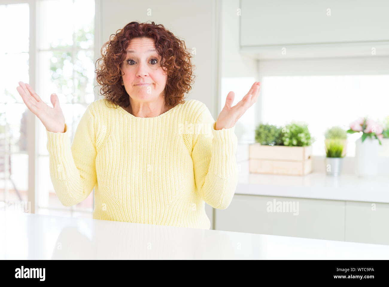 Beautiful senior woman wearing yellow sweater clueless and confused ...