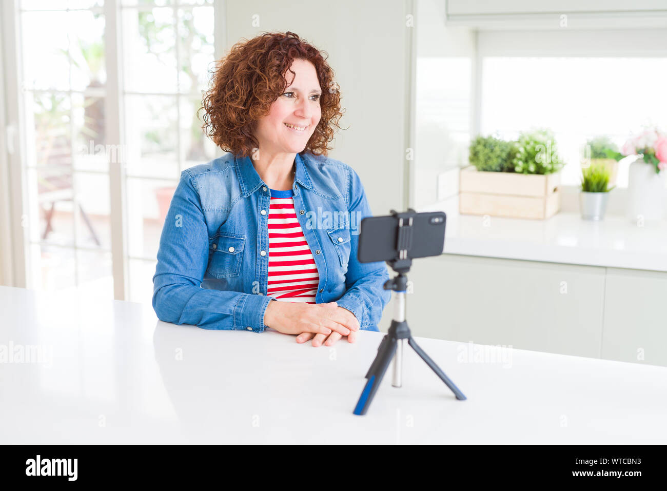 Senior woman doing video chat using smartphone camera looking away to ...