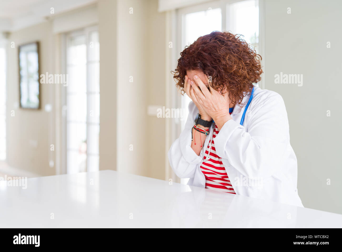 Senior doctor woman wearing medical robe at the clinic with sad ...
