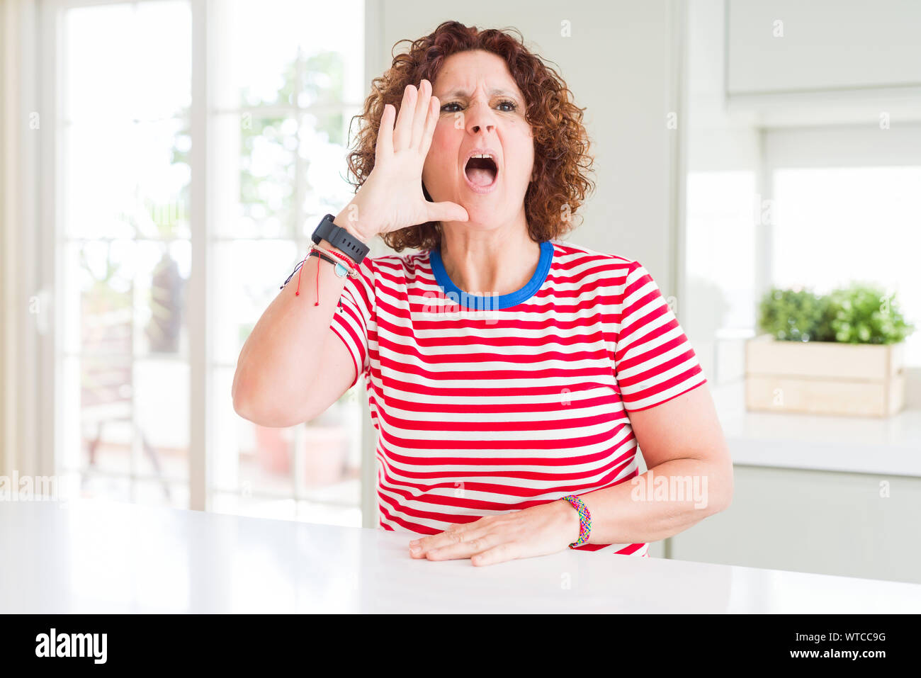 Beautiful senior woman sitting at home shouting and screaming loud to ...