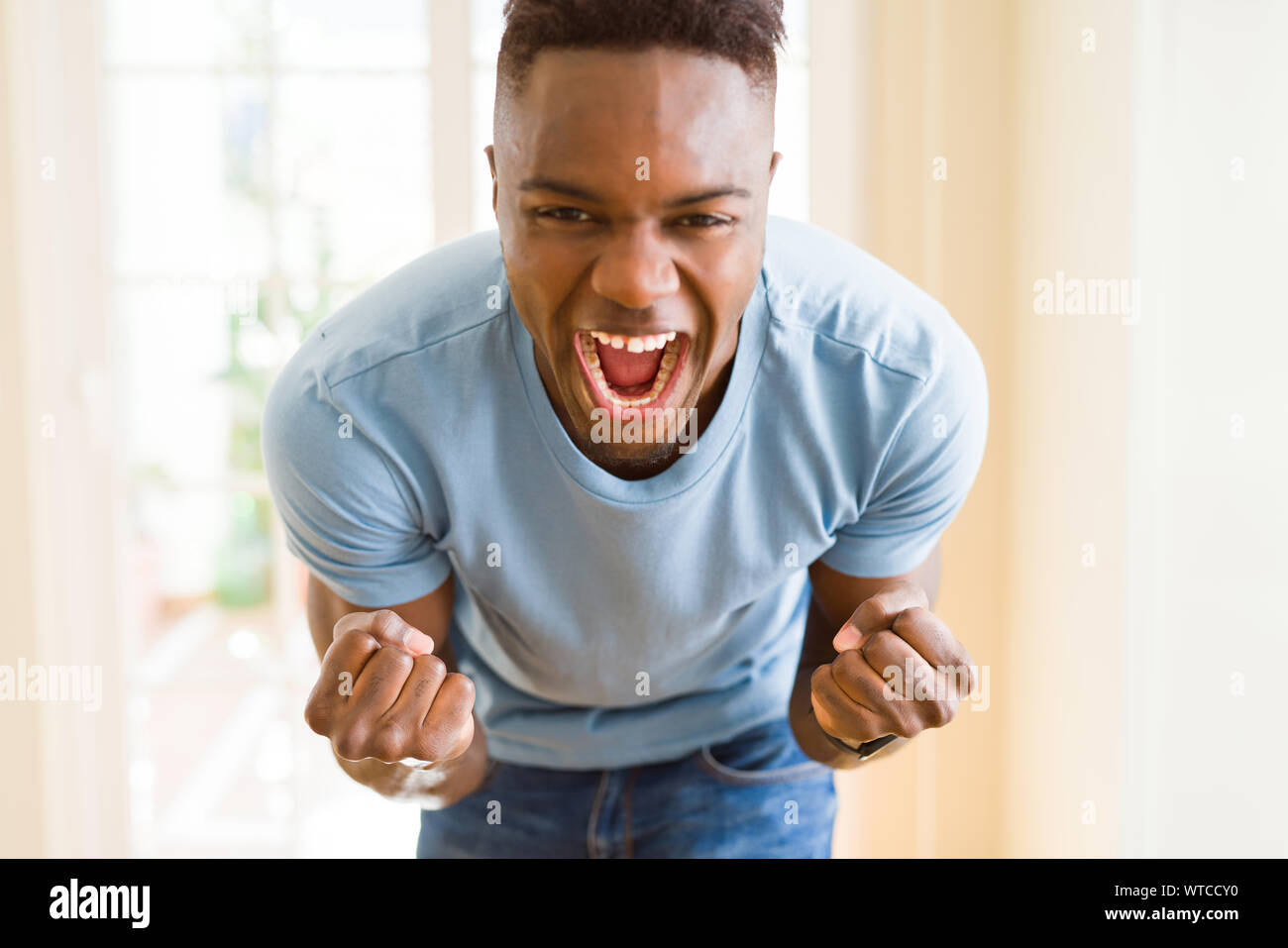 African American man screaming very excited and celebrating success and ...