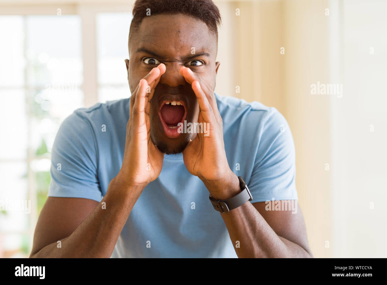 African american man shouting with rage, yelling excited with hand on ...