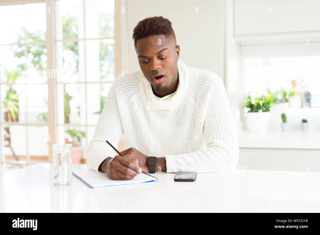 African american student man writing on a paper using a pencil scared ...
