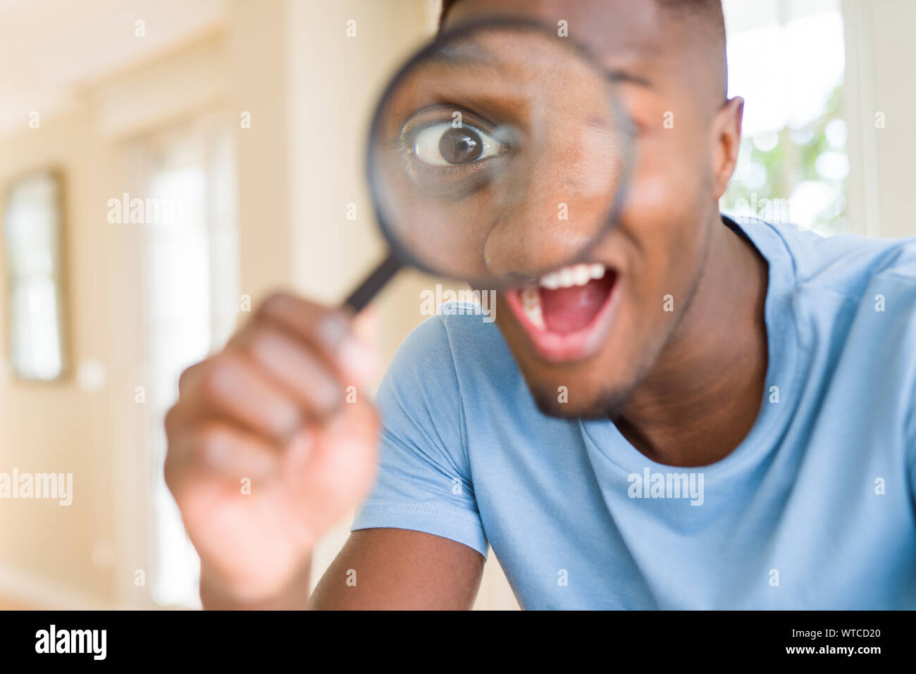 Young african man looking through magnifying glass Stock Photo - Alamy