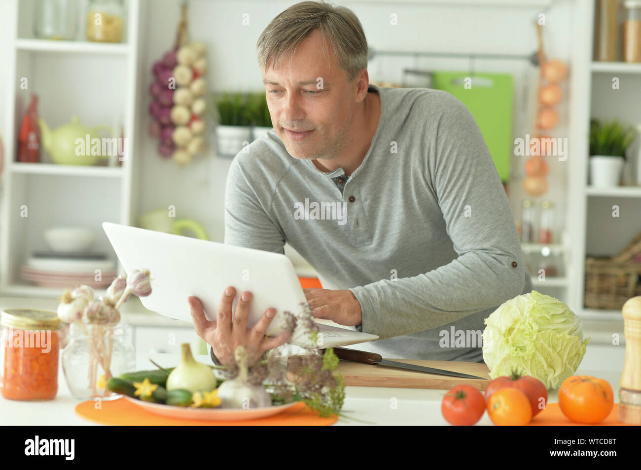 Elderly male chef using laptop while cooking at kitchen Stock Photo - Alamy