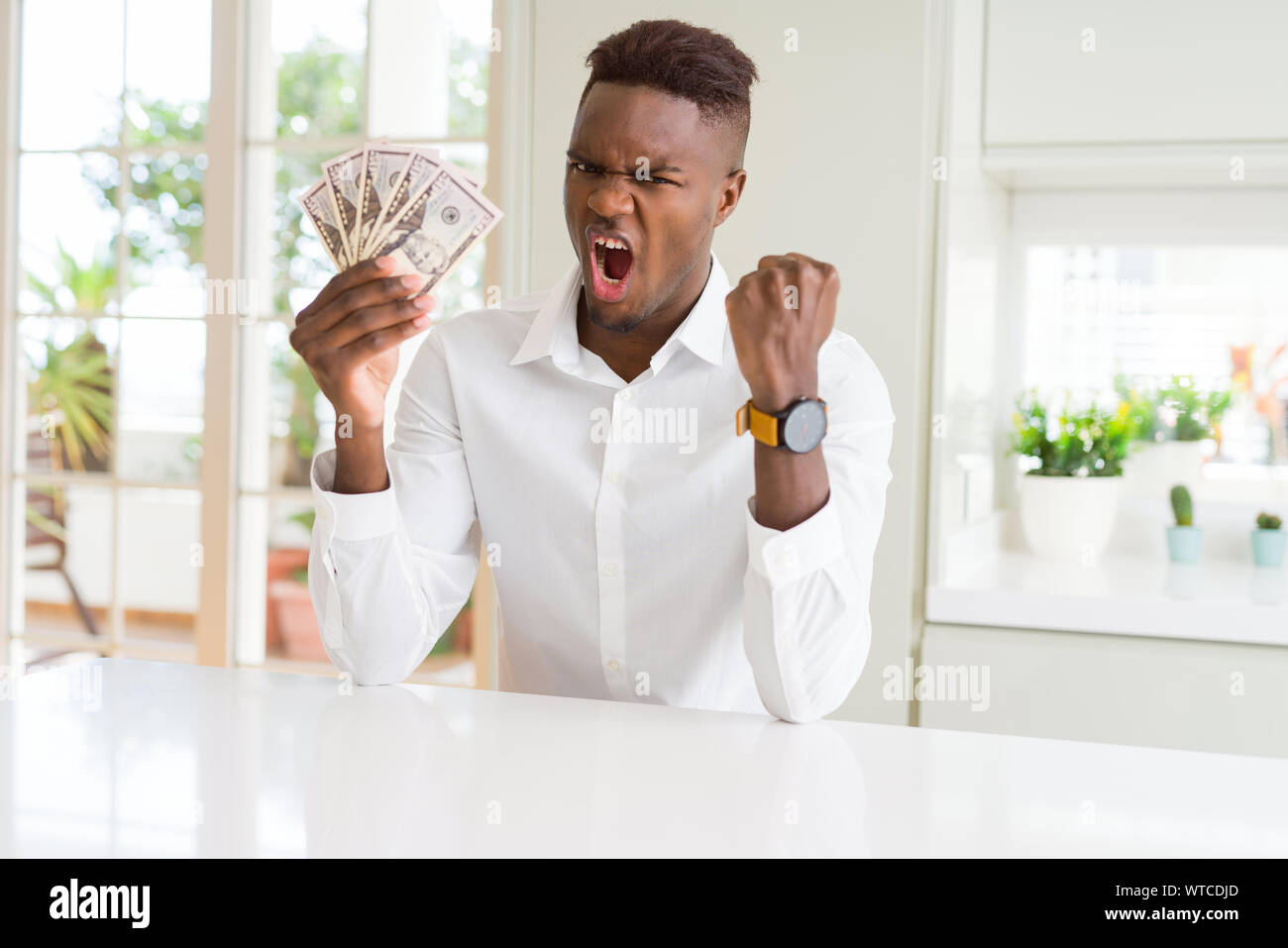 African american man holding fifty dollars bank notes annoyed and ...
