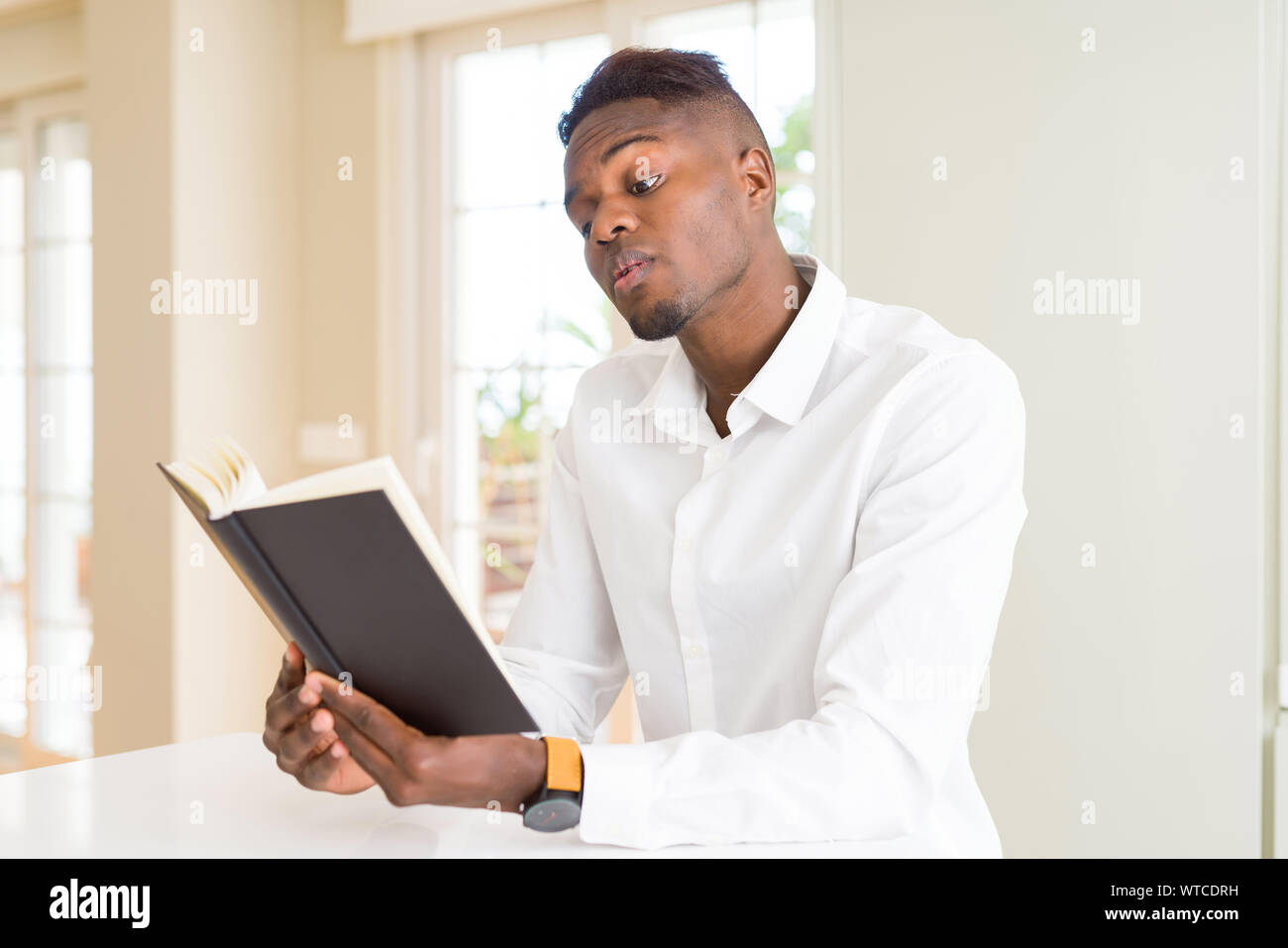 Young african man reading a book, studying for univeristy Stock Photo ...