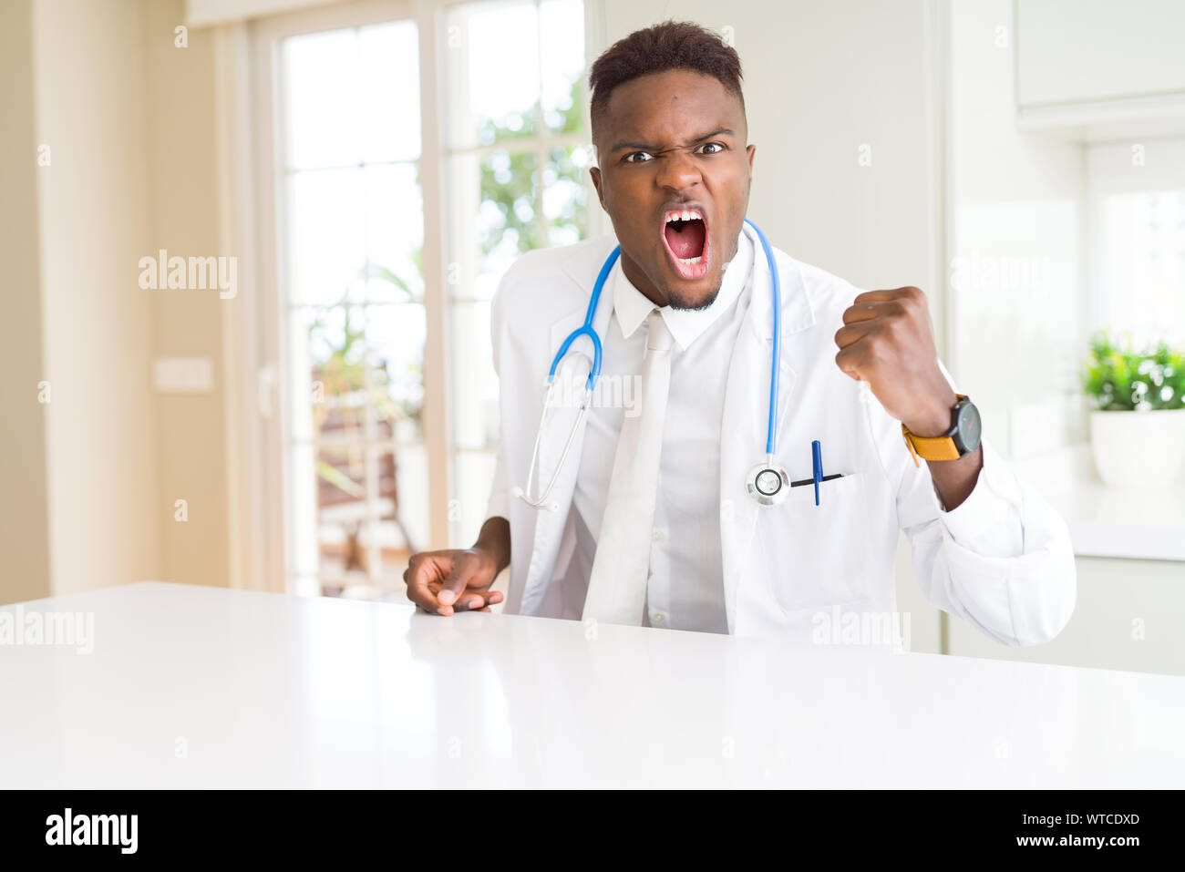 African american doctor man at the clinic angry and mad raising fist ...