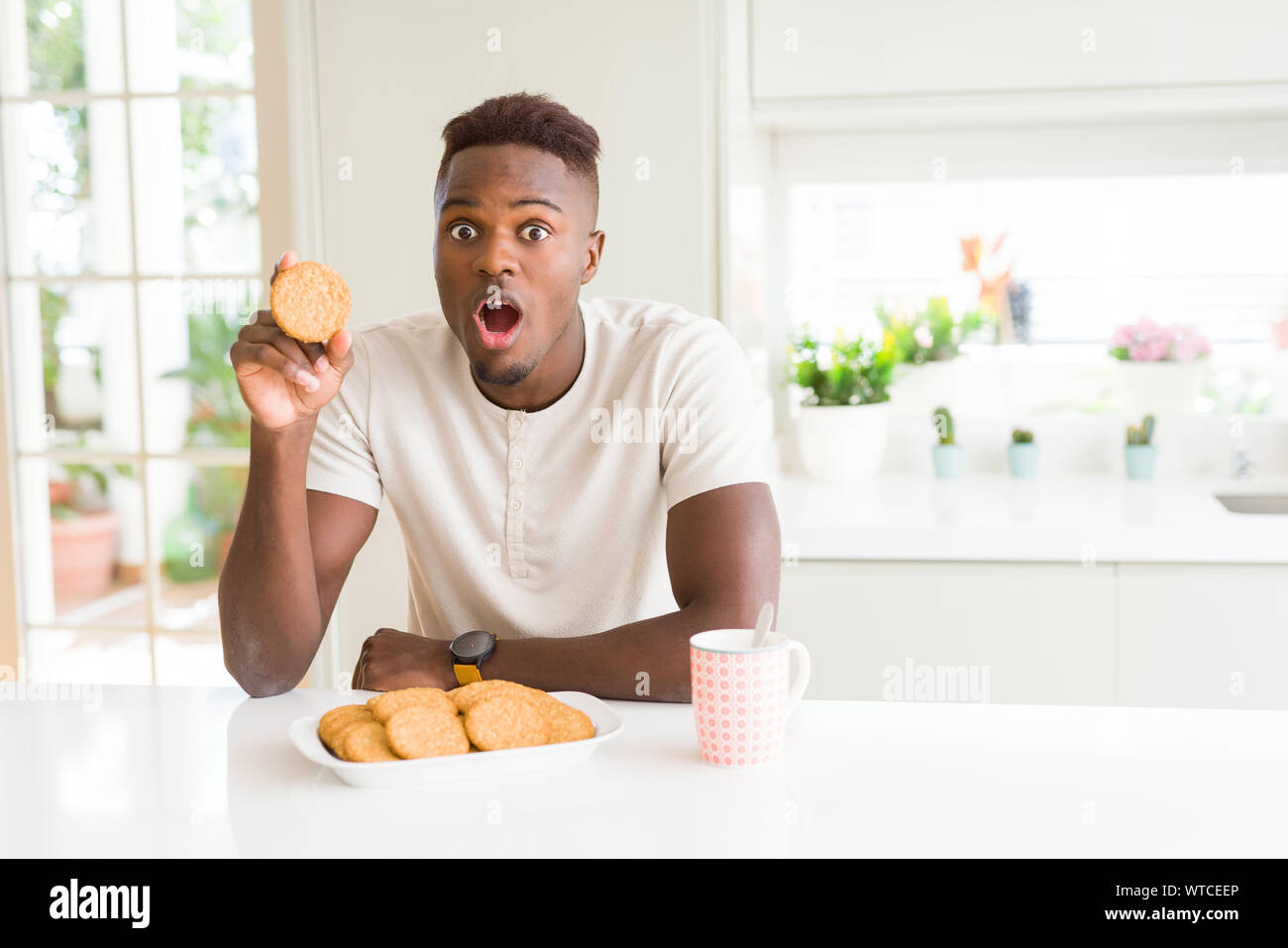African american man eating healthy whole grain biscuit scared in shock ...