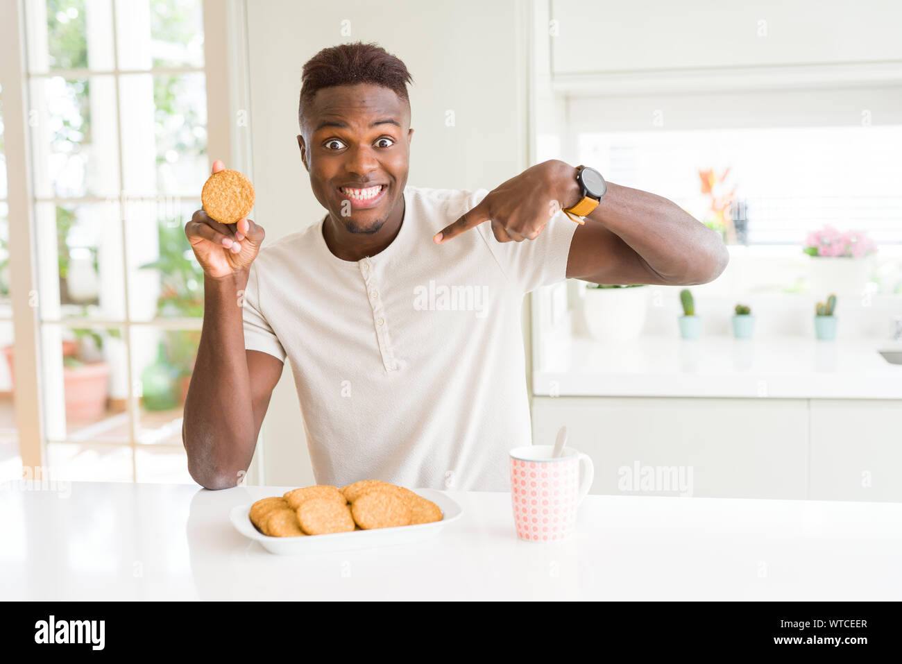 African american man eating healthy whole grain biscuit with surprise ...