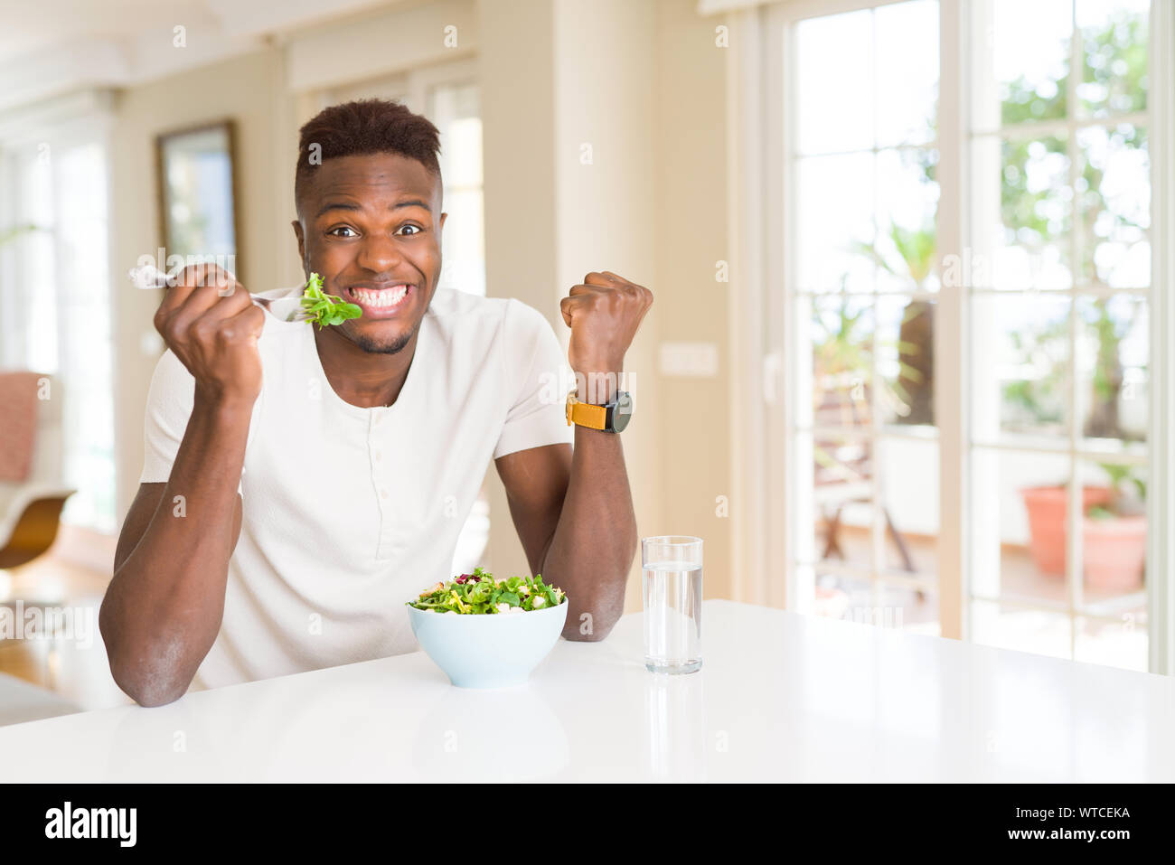 African american man eating fresh healthy salad screaming proud and ...