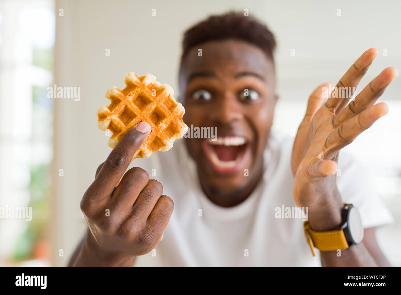 African american man eating sweet Belgian waffle very happy and excited ...