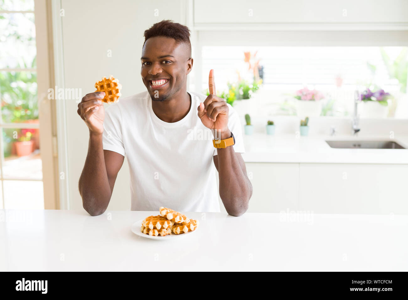 African american man eating sweet Belgian waffle surprised with an idea ...