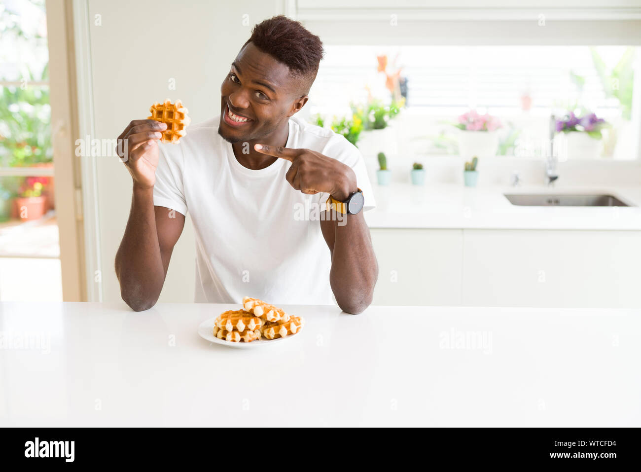 African american man eating sweet Belgian waffle very happy pointing ...