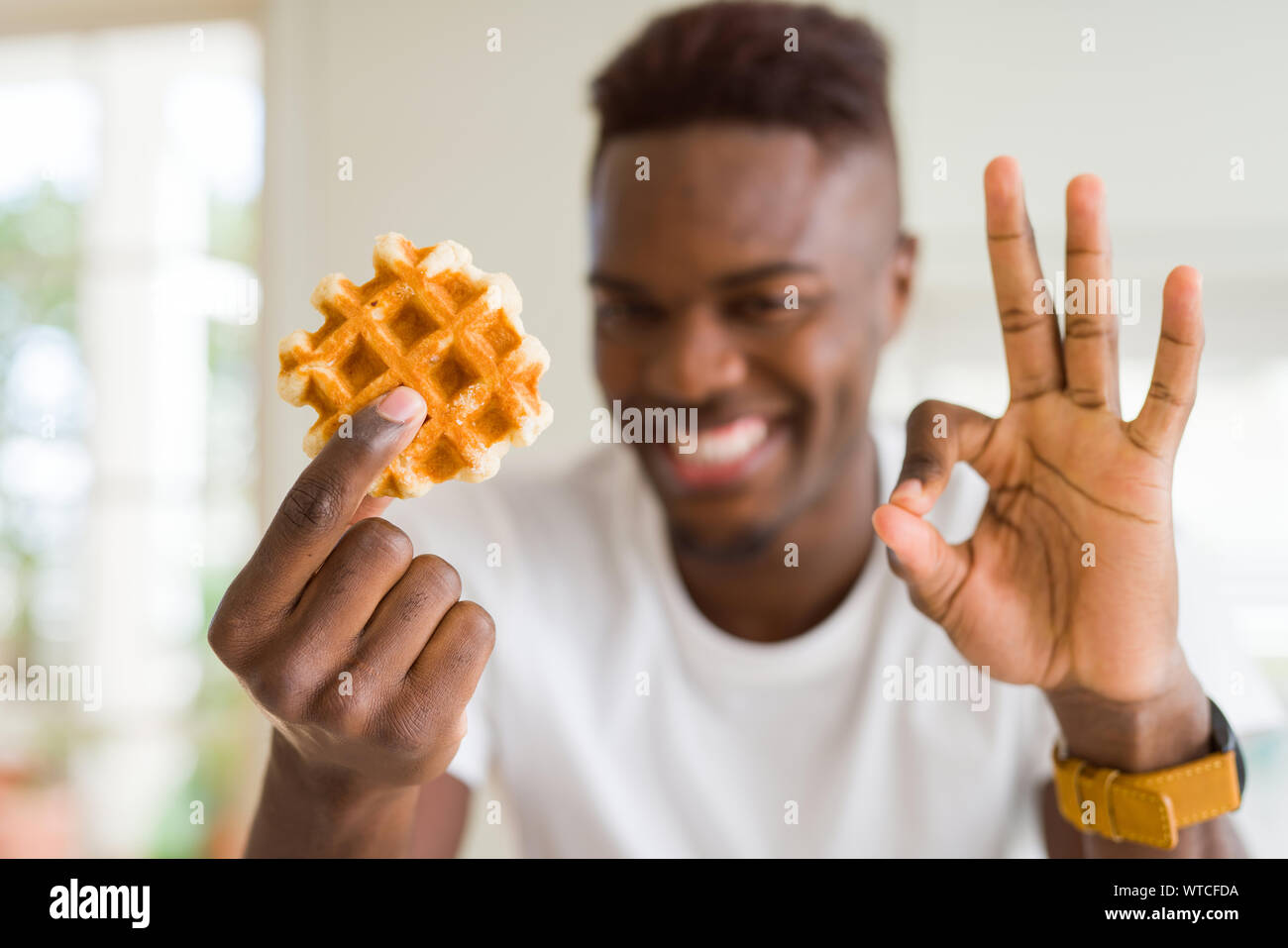 African american man eating sweet Belgian waffle doing ok sign with ...