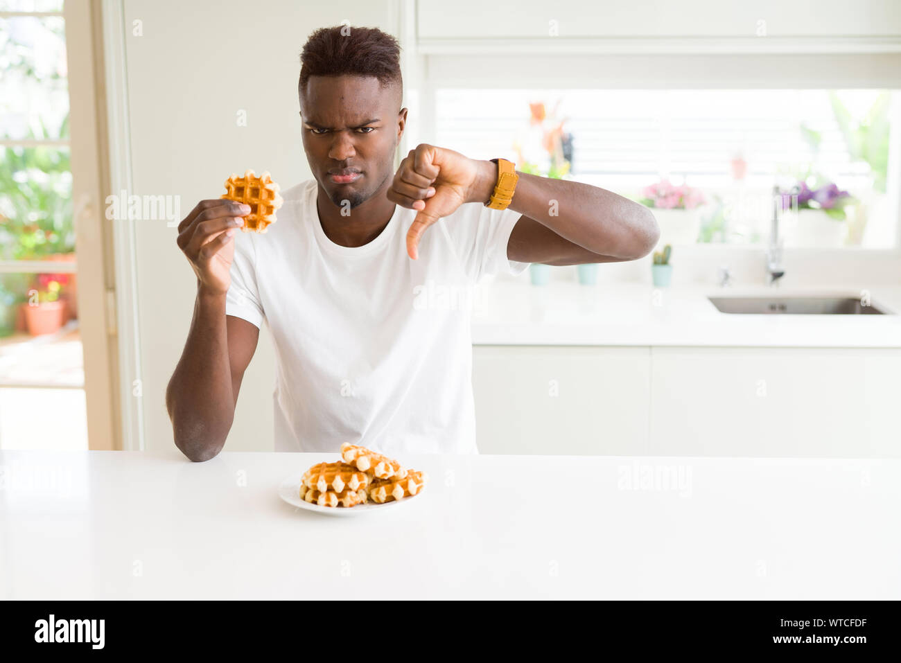 African american man eating sweet Belgian waffle with angry face ...