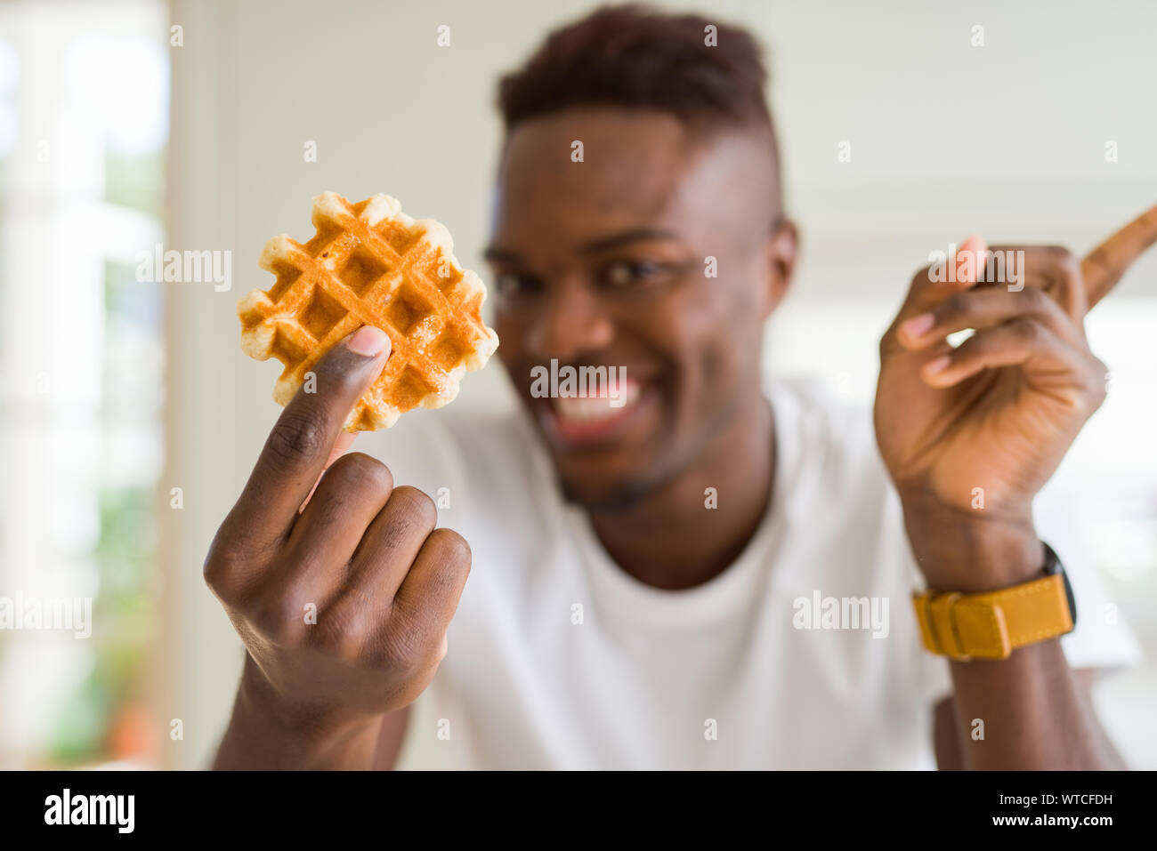 African american man eating sweet Belgian waffle very happy pointing ...