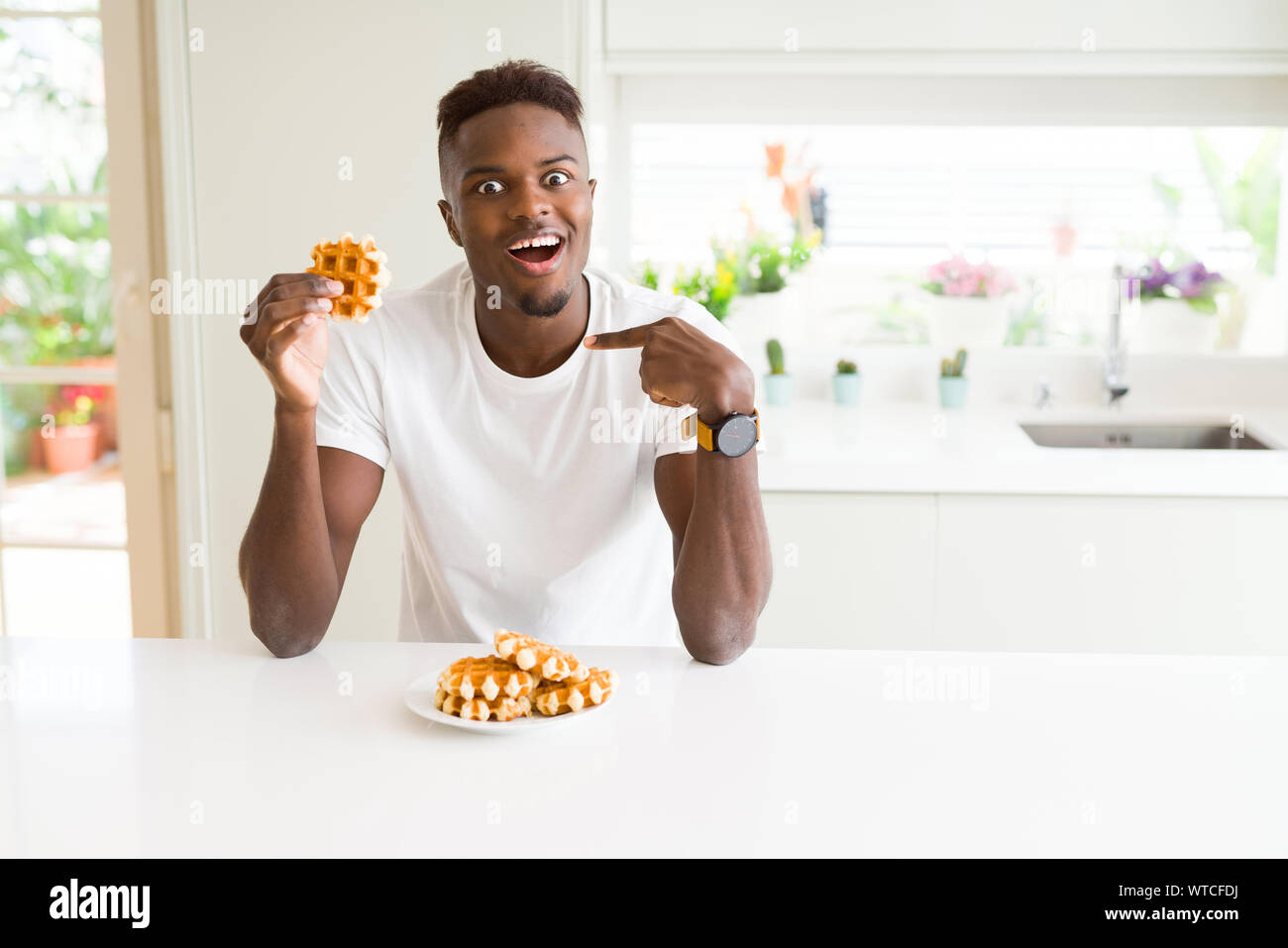 African american man eating sweet Belgian waffle with surprise face ...