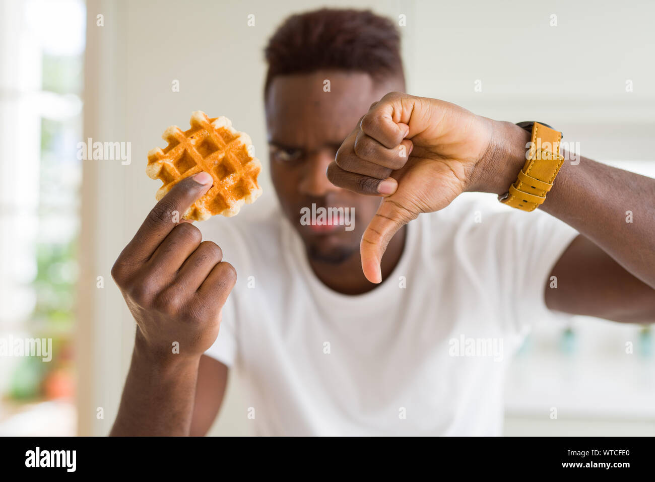 African american man eating sweet Belgian waffle with angry face ...