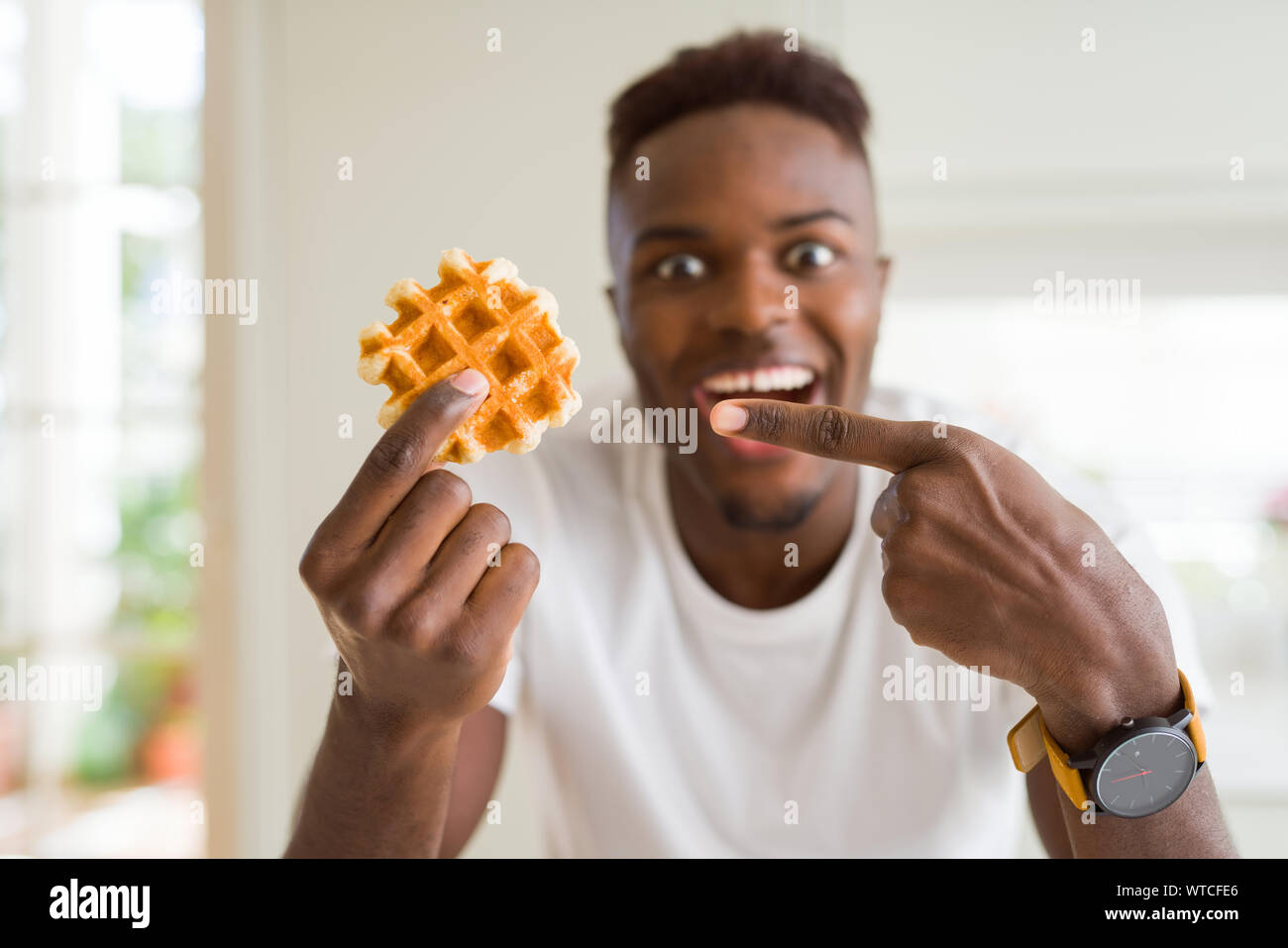 African american man eating sweet Belgian waffle very happy pointing ...