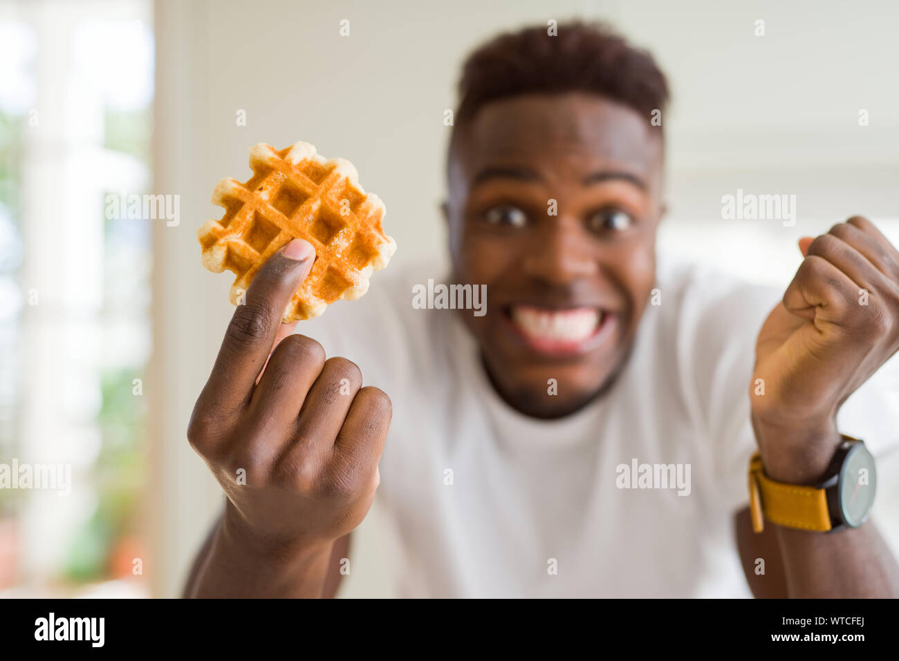 African american man eating sweet Belgian waffle screaming proud and ...