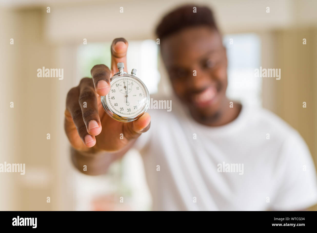 Young african man holding silver retro stopwatch counting time Stock ...