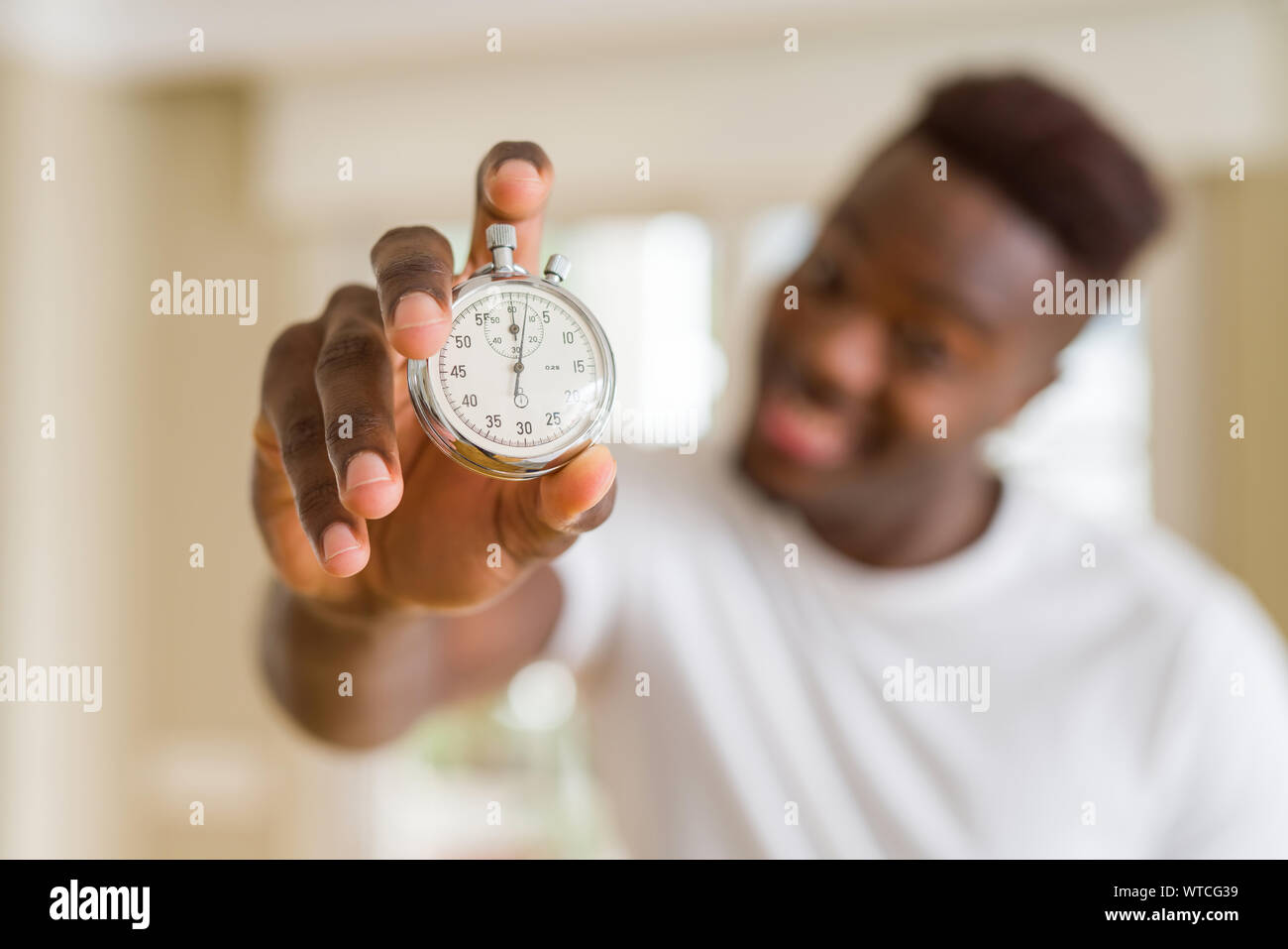 Young african man holding silver retro stopwatch counting time Stock ...