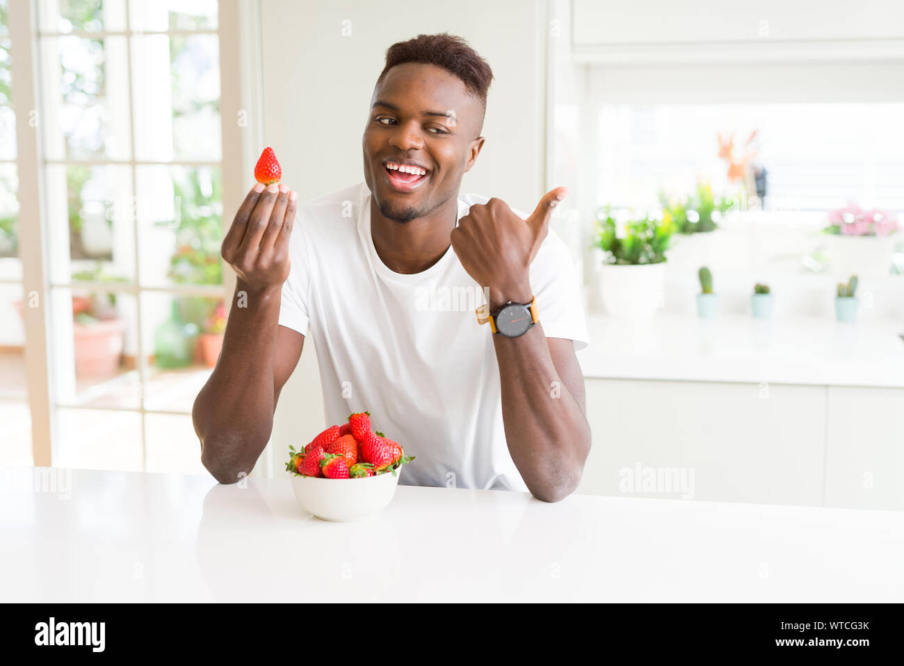 African american man eating fresh healthy strawberries pointing and ...