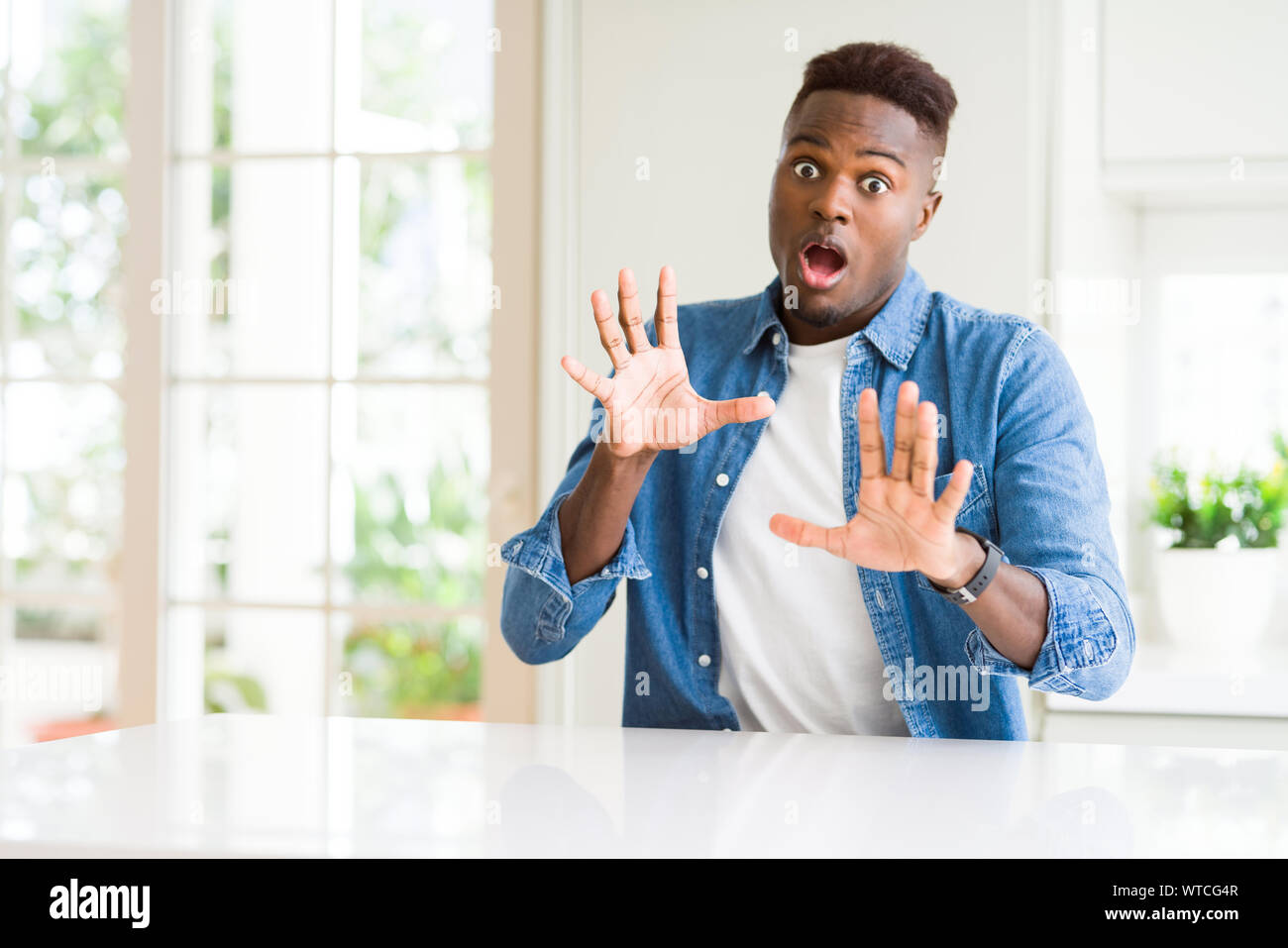 Handsome african american man at home afraid and terrified with fear ...