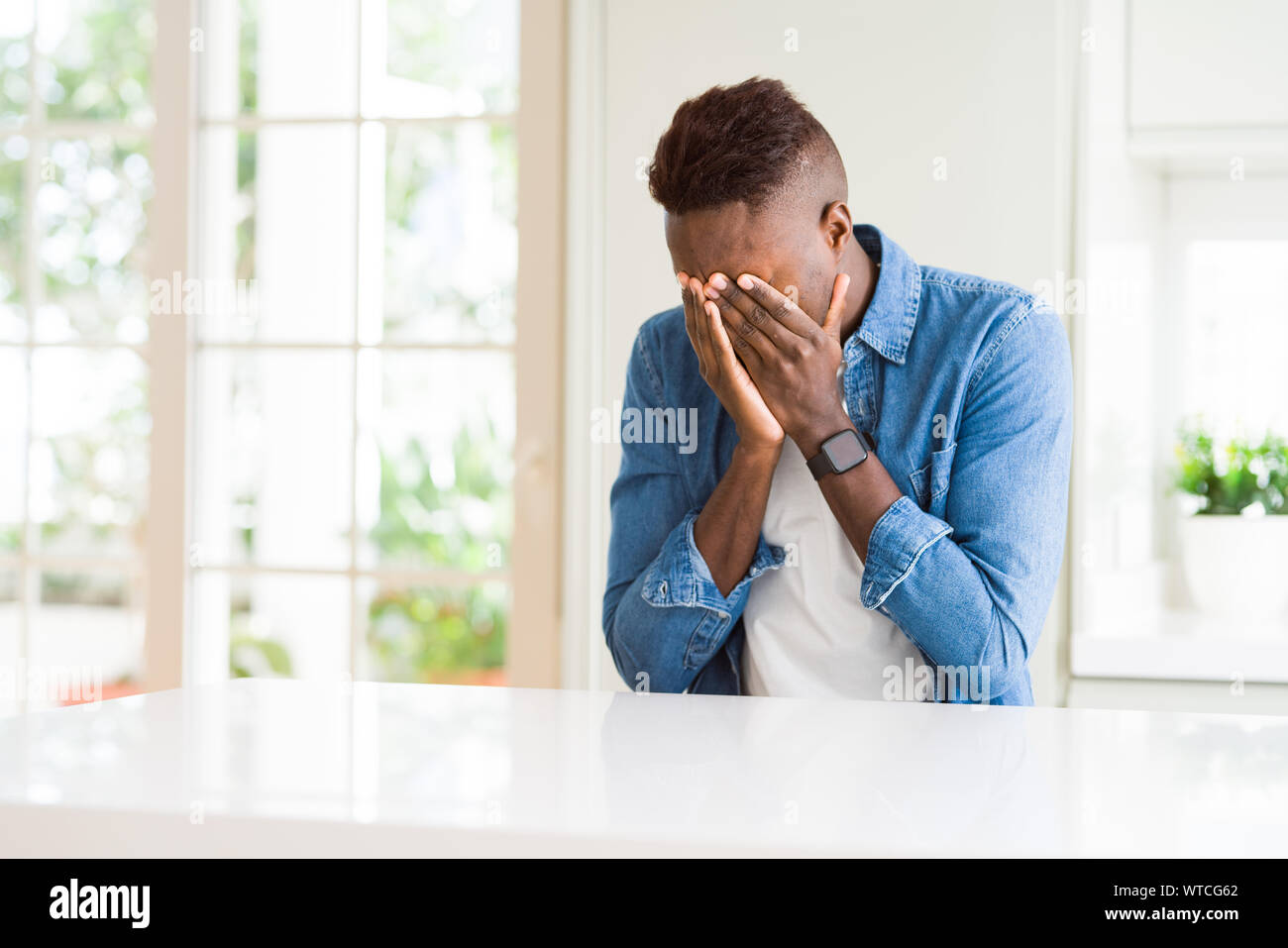 Handsome african american man at home with sad expression covering face ...