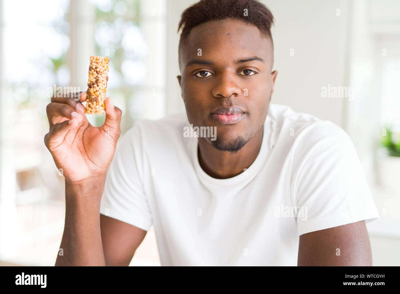 African american man eating energetic cereals bar with a confident ...