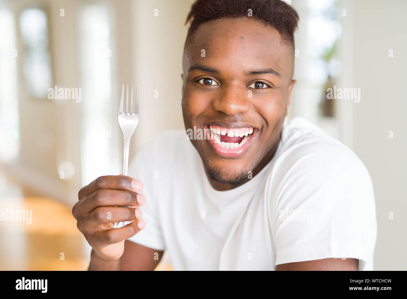 African american man holding silver fork cutlery with a happy face ...
