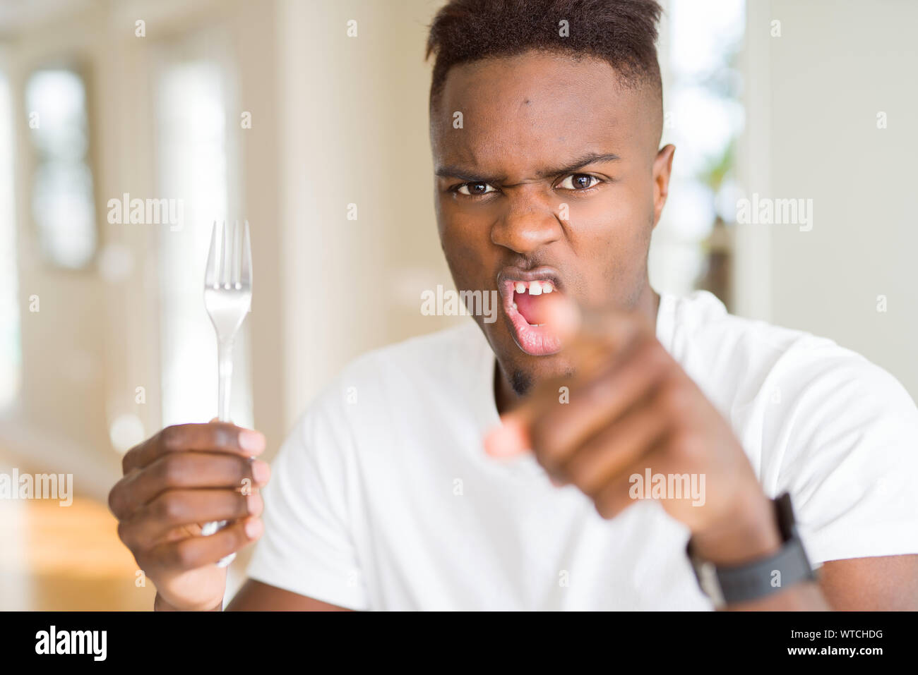 African american man holding silver fork cutlery pointing with finger ...
