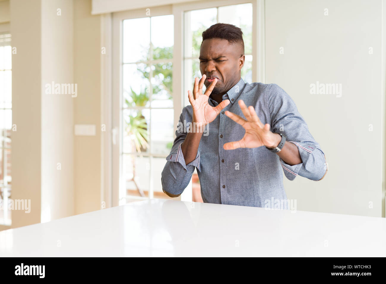 Handsome african american man on white table disgusted expression ...