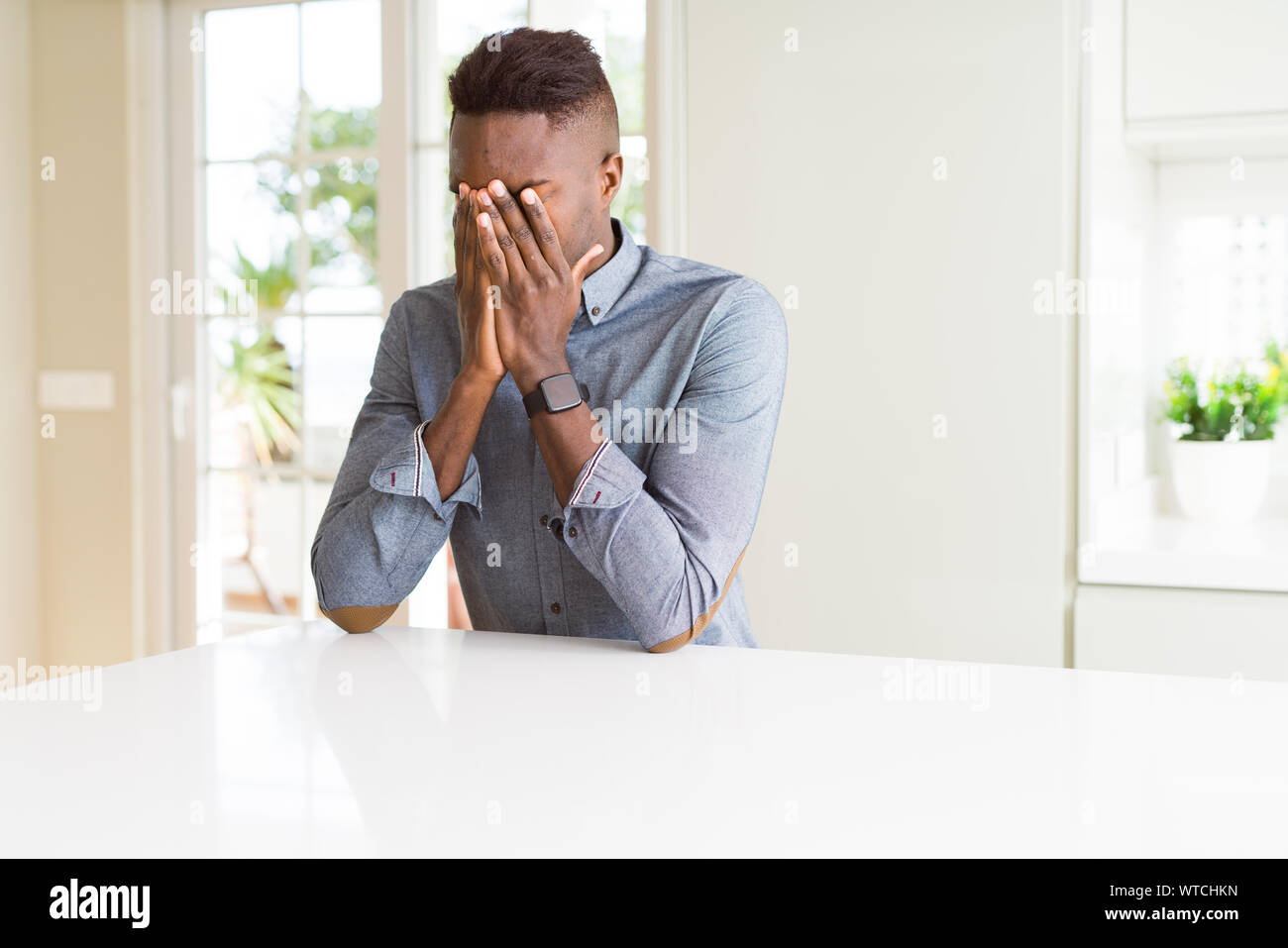 Handsome african american man on white table with sad expression ...