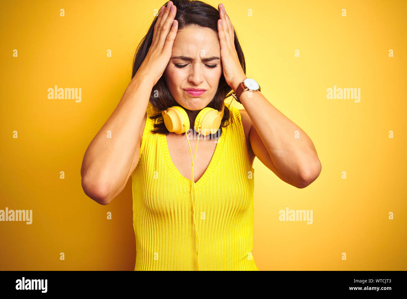 Young beautiful woman wearing headphones over yellow isolated ...