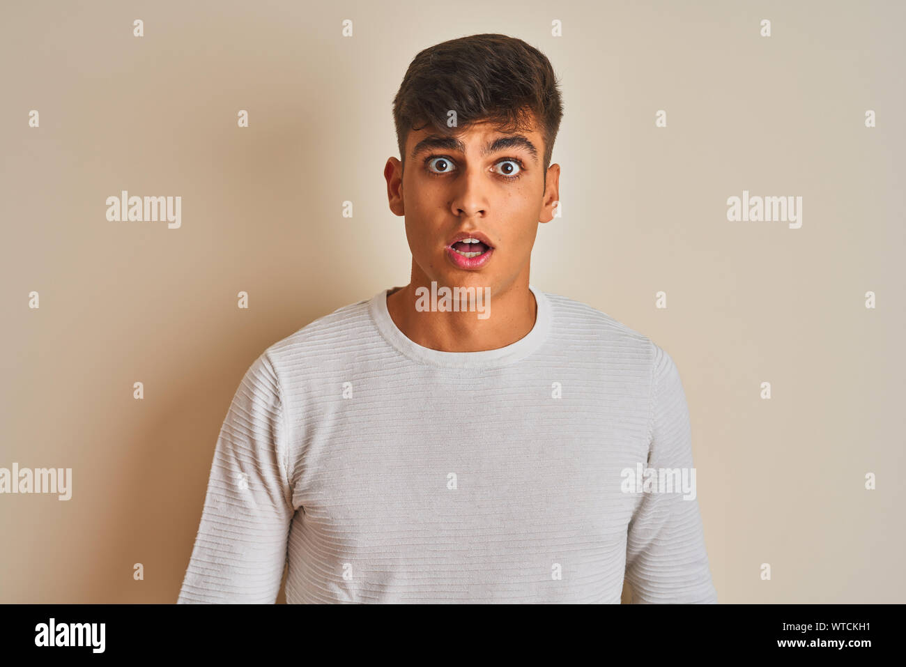 Young indian man wearing sweater standing over isolated white background afraid and shocked with ...
