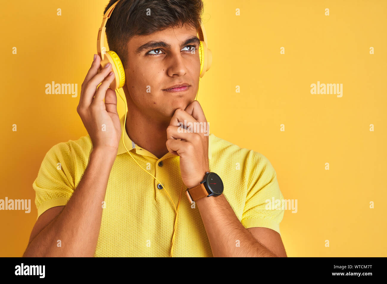 Young indian man listening to music using headphones over isolated ...