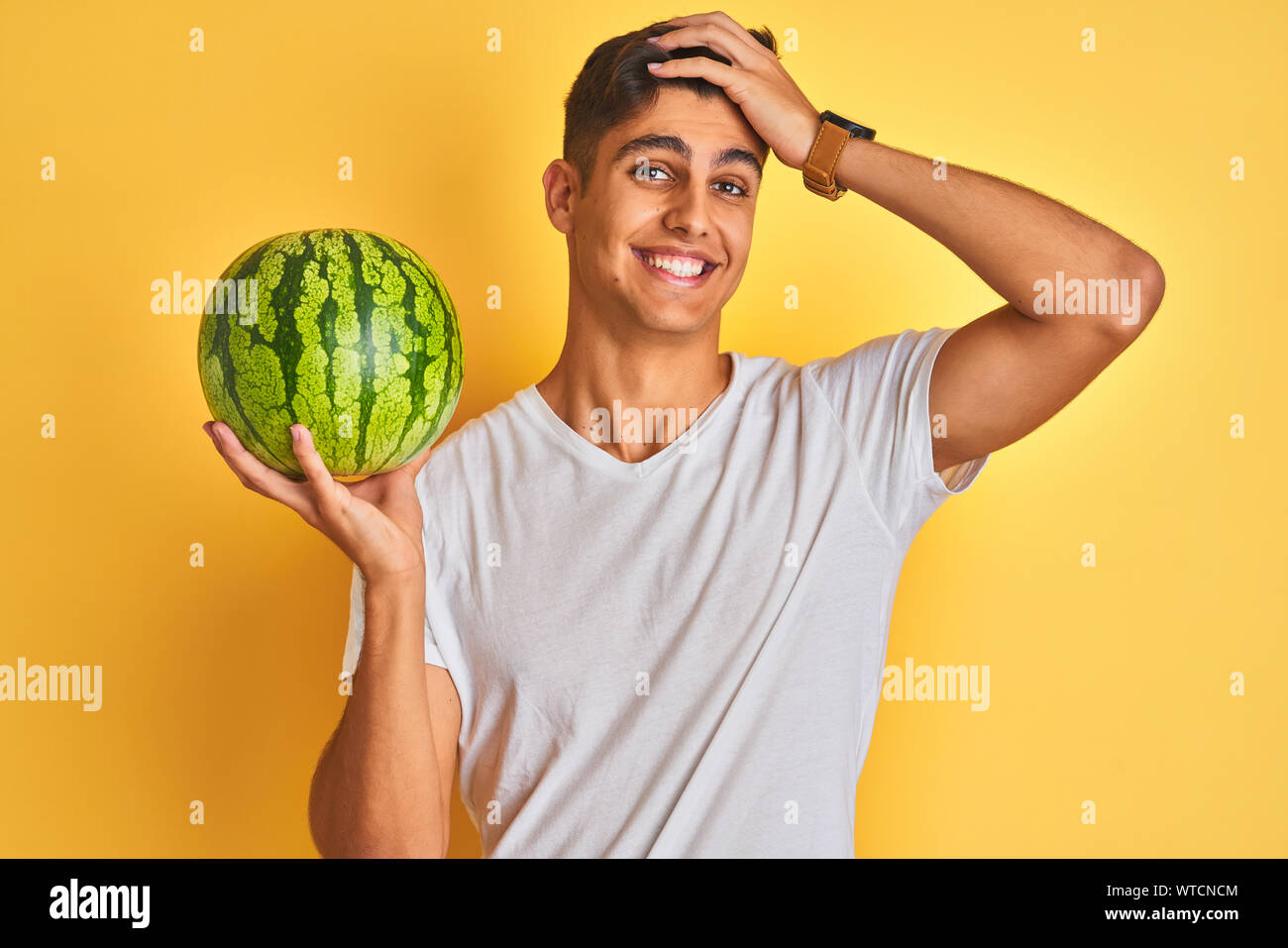 Young indian shopkeeper man holding watermelon standing over isolated ...