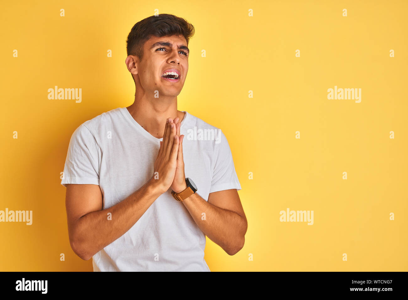 Young indian man wearing white t-shirt standing over isolated yellow ...