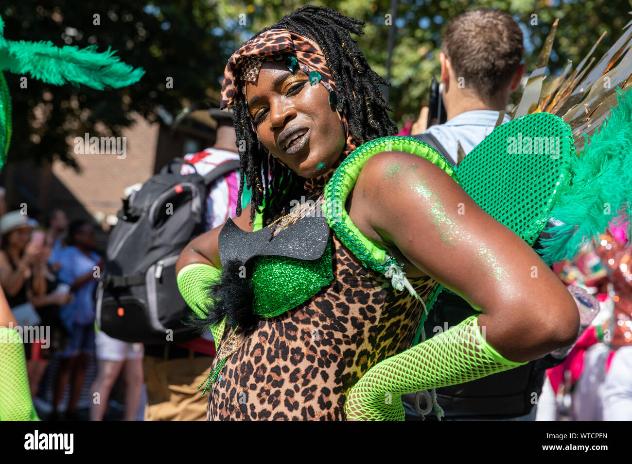 A parade goer dressed in a leopard print top with green feathered wings ...
