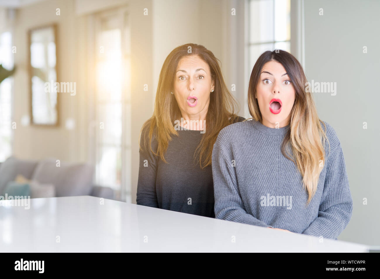 Beautiful family of mother and daughter together at home afraid and ...