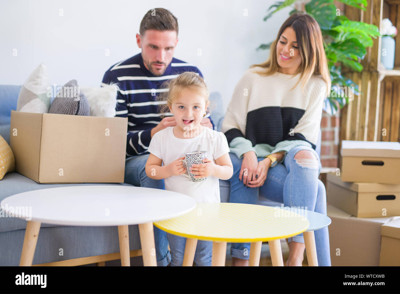 Beautiful family, parents sitting on the sofa drinking coffee looking ...