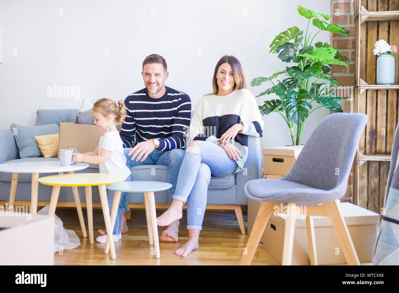 Beautiful family, parents sitting on the sofa drinking coffee looking ...